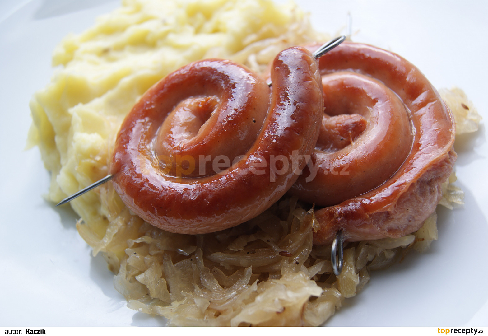 Vinná klobása pečená na zelí s karamelizovanou cibulkou - TopRecepty.cz